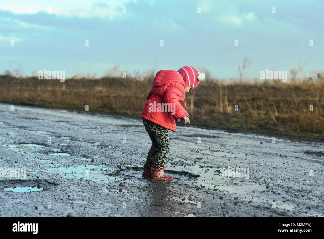 Concept - happy childhood. Little girl plays in puddle, children's fun ...