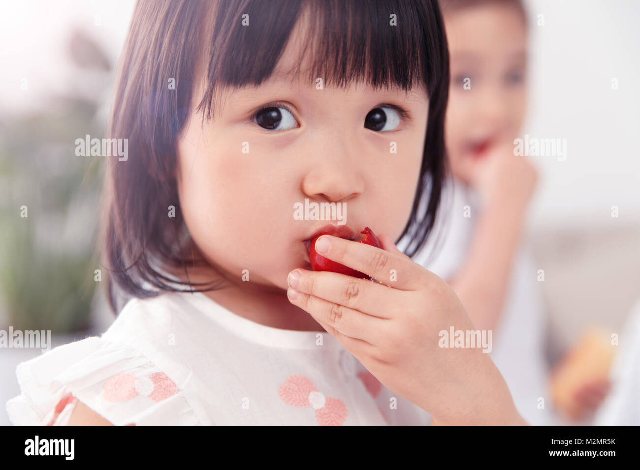 The lovely little girl is eating fruit Stock Photo - Alamy