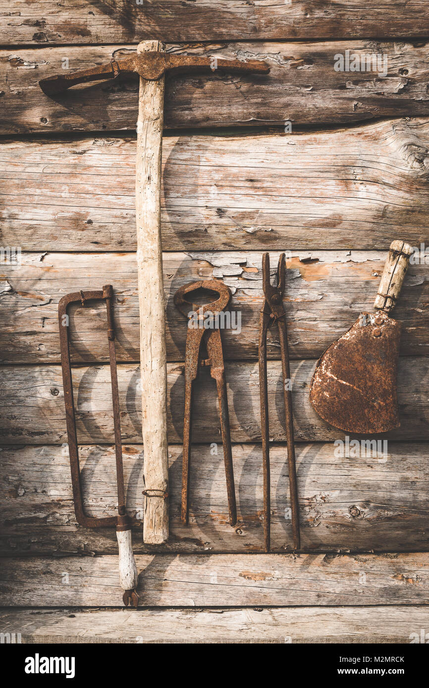 Collection of vintage rusty tools displayed on a old wooden background ...