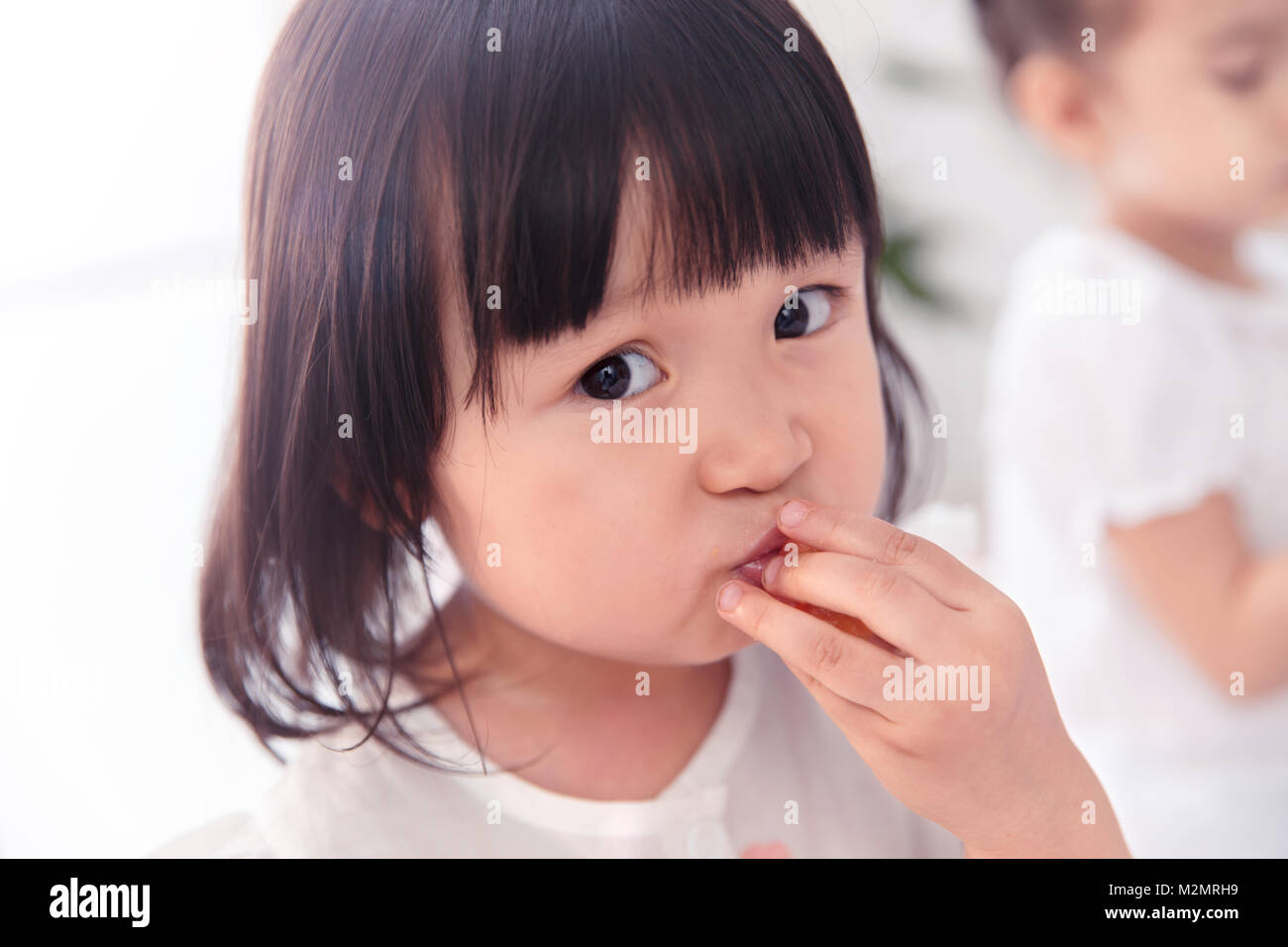 The lovely little girl is eating fruit Stock Photo - Alamy