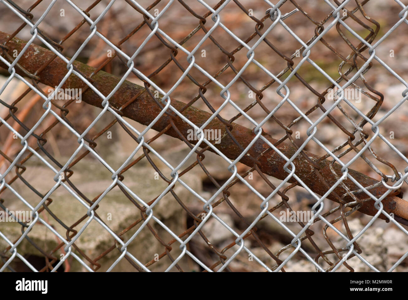 Rusty chain link fence with a brown and grey urban background blurred ...