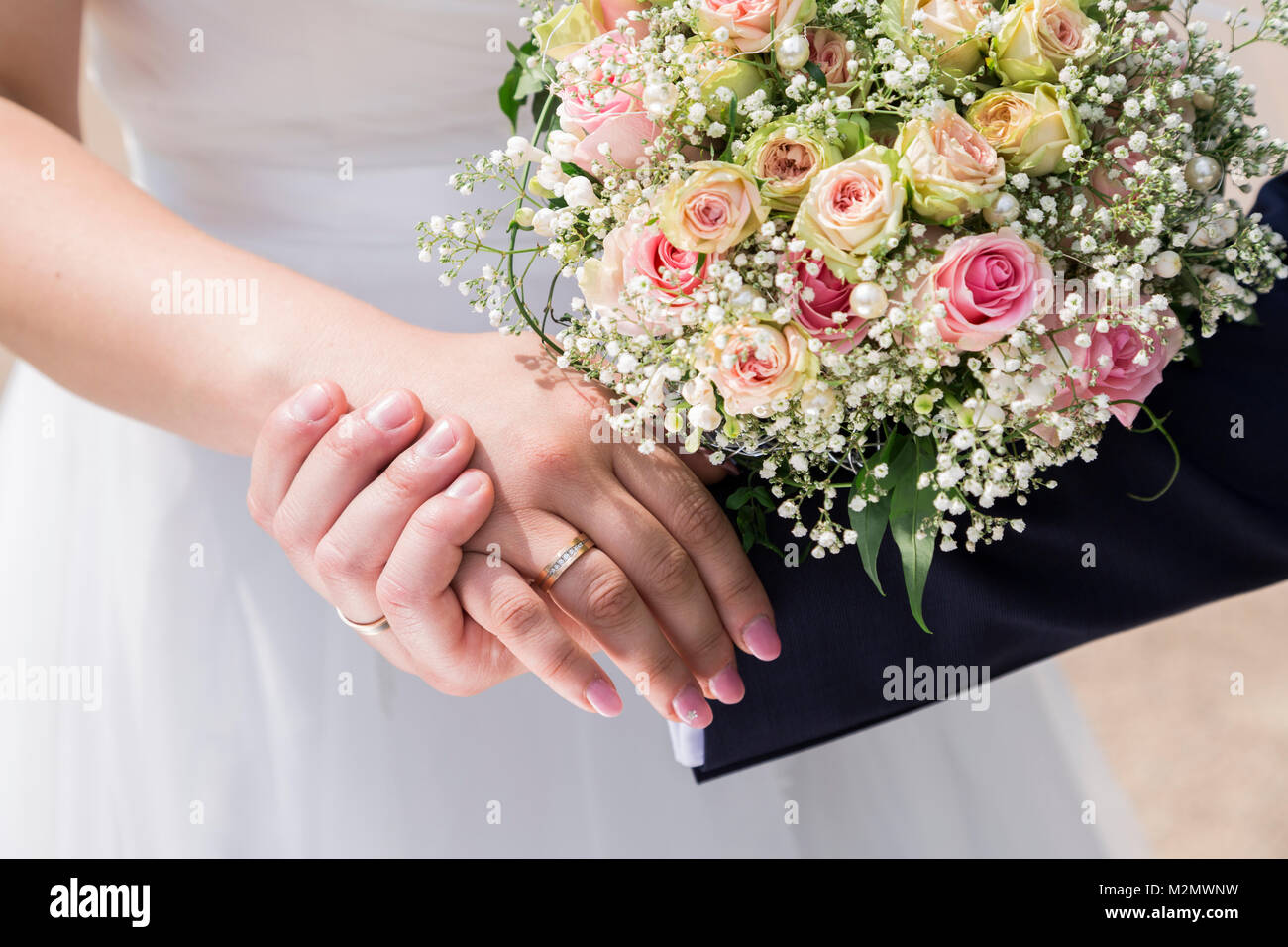 Hand of groom in a blue suit and hand of bride in white wedding dress ...