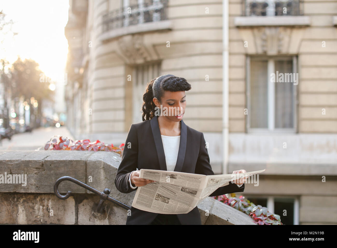 Half Nigerian reporter looking at cam with newspaper on balcony Stock ...