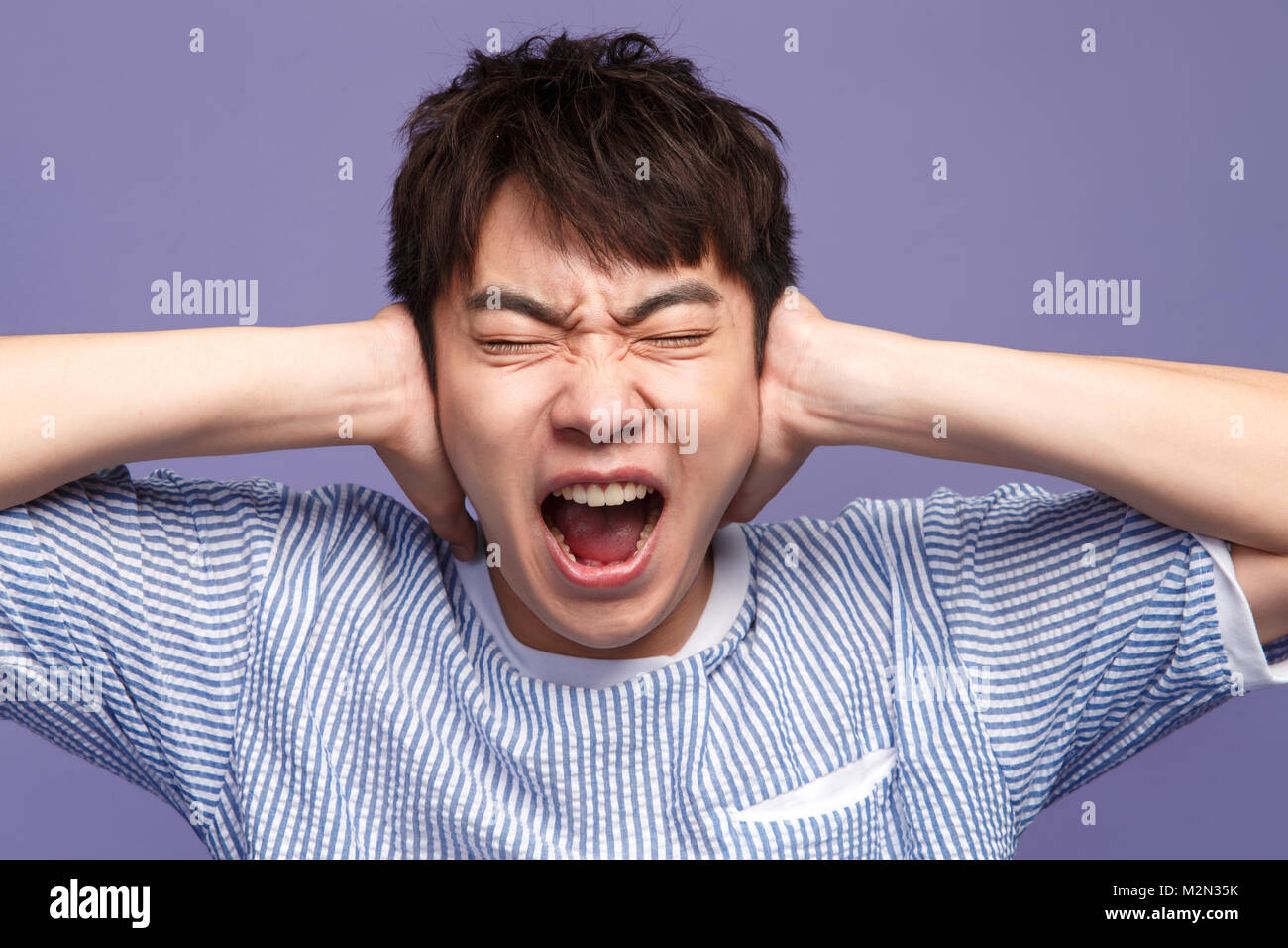 The young man screaming covering her ears Stock Photo - Alamy