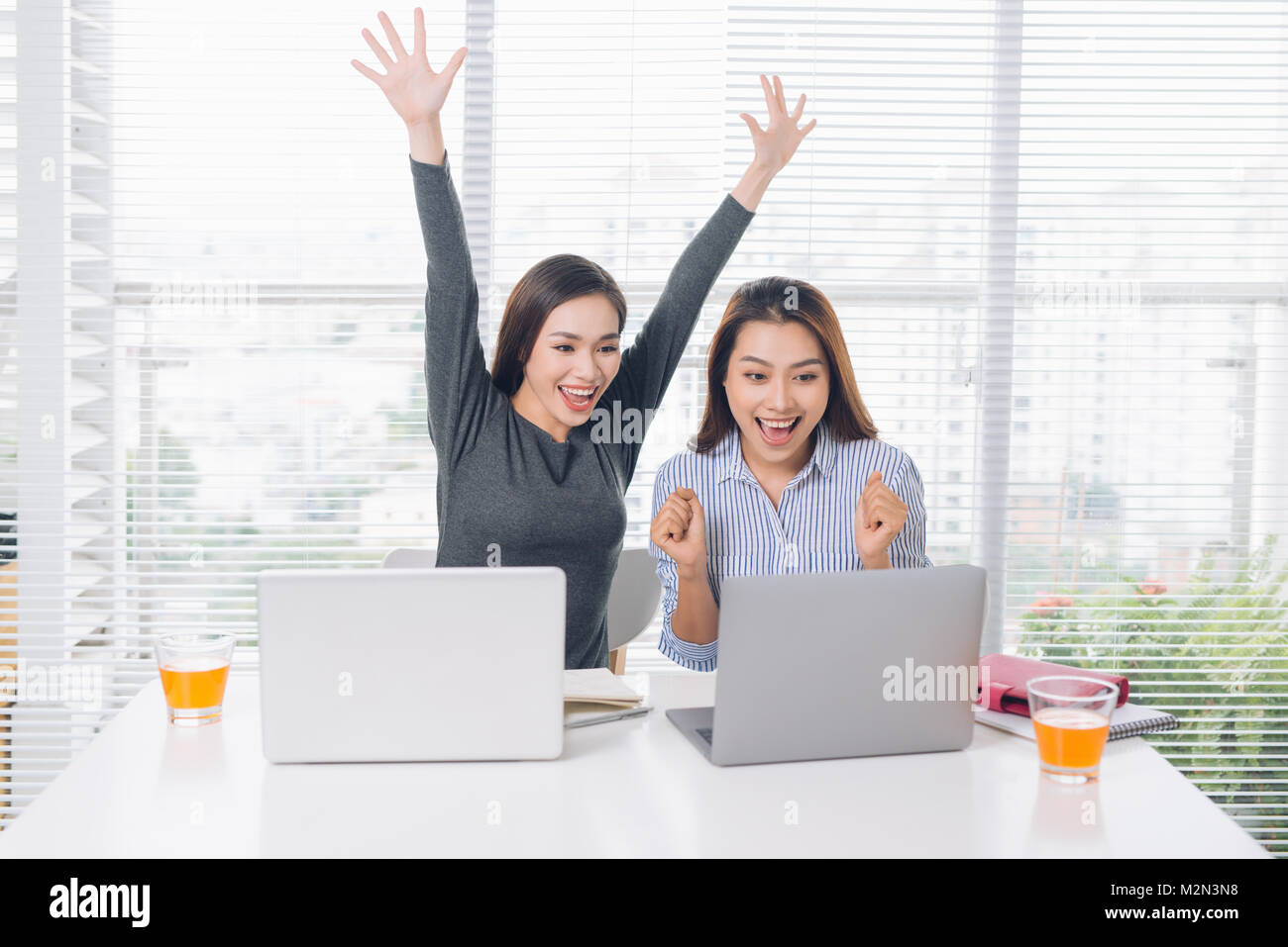 Businesswomen with laptop computer and papers showing thumbs up and ...