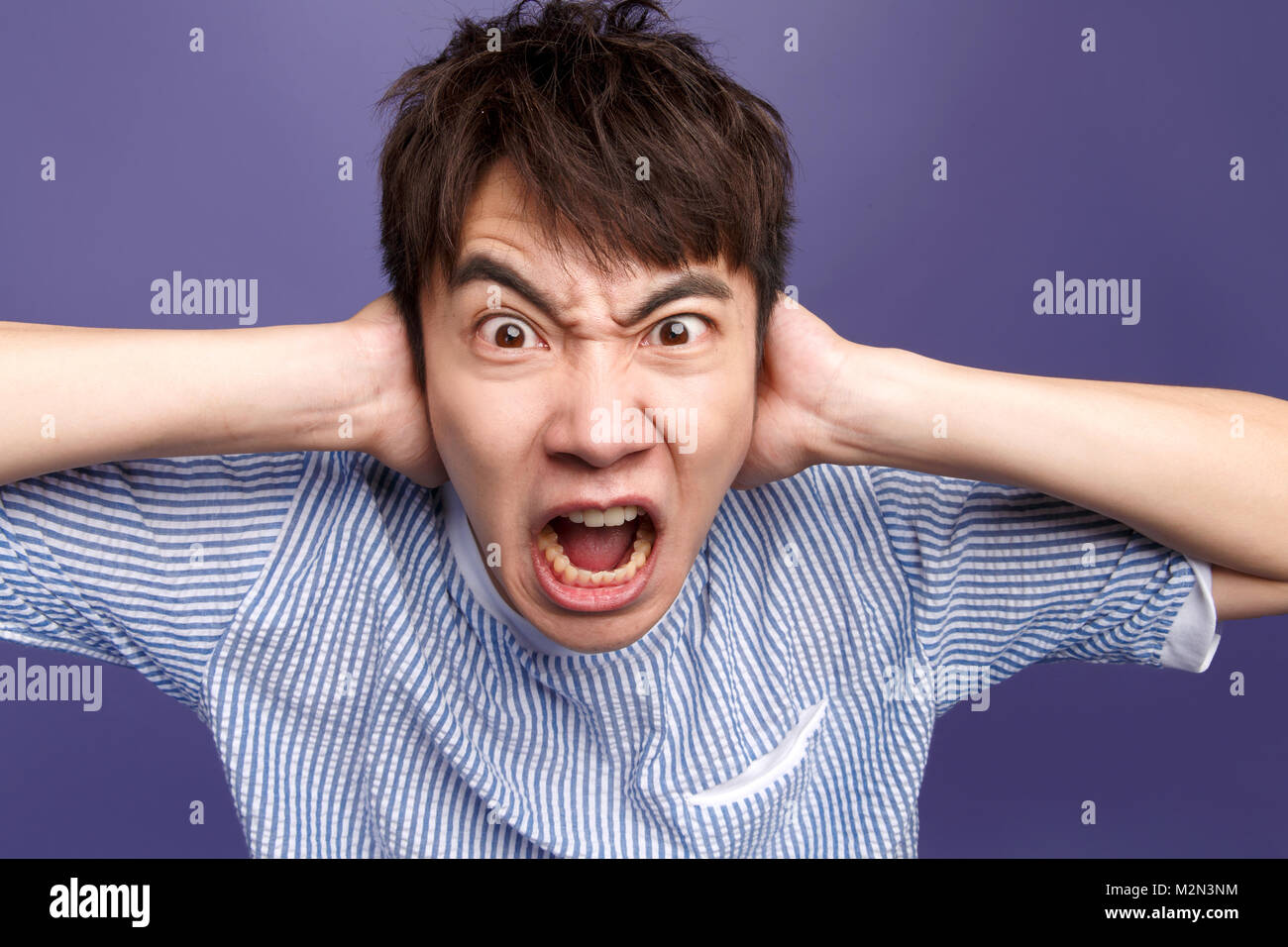 The young man screaming covering her ears Stock Photo - Alamy