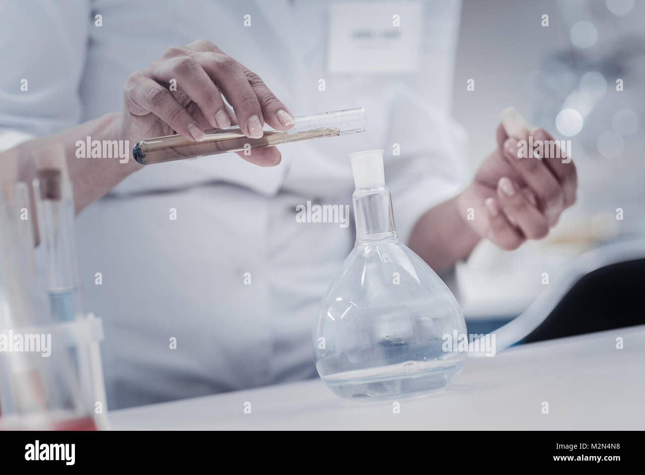 Scaled up look on female chemist pouring liquid into flask Stock Photo ...