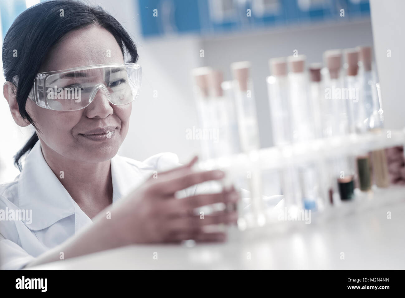 Satisfies female scientist examining test tubes with liquids Stock ...