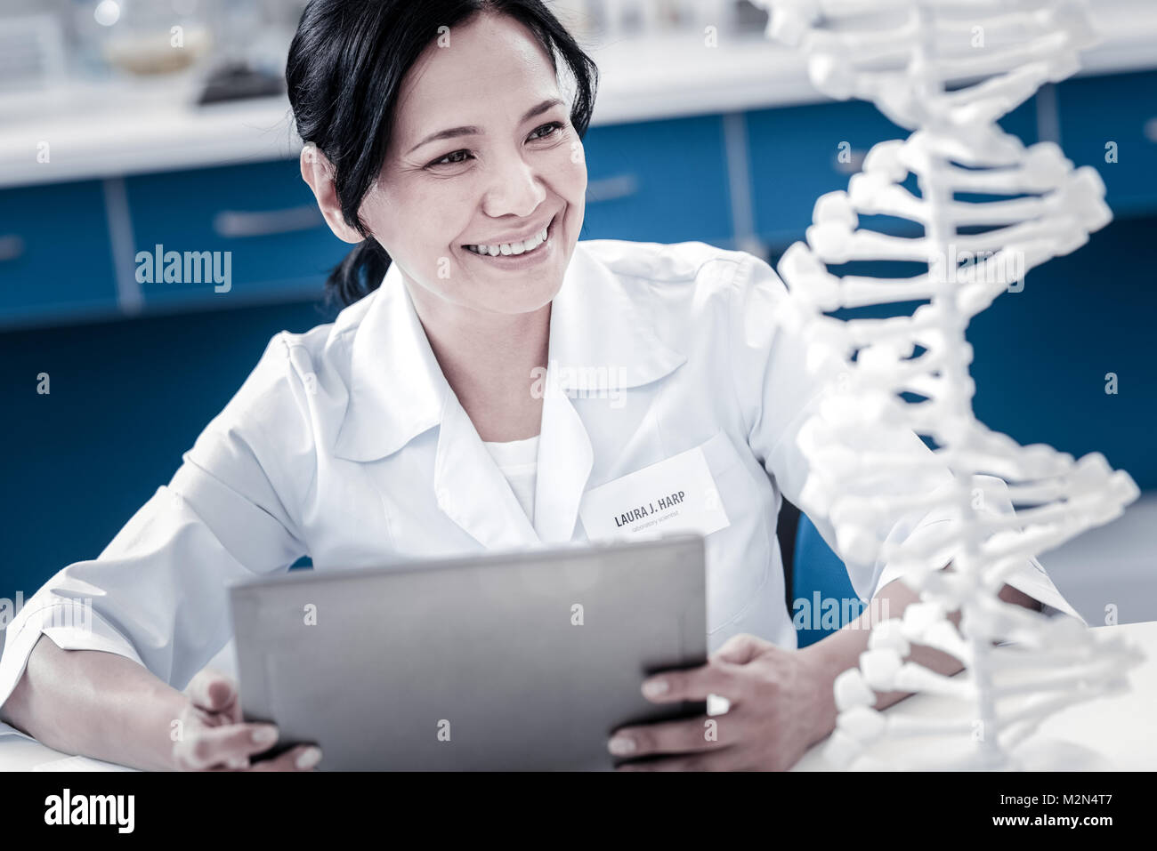Beaming mature lady with touchpad looking at dna model Stock Photo - Alamy