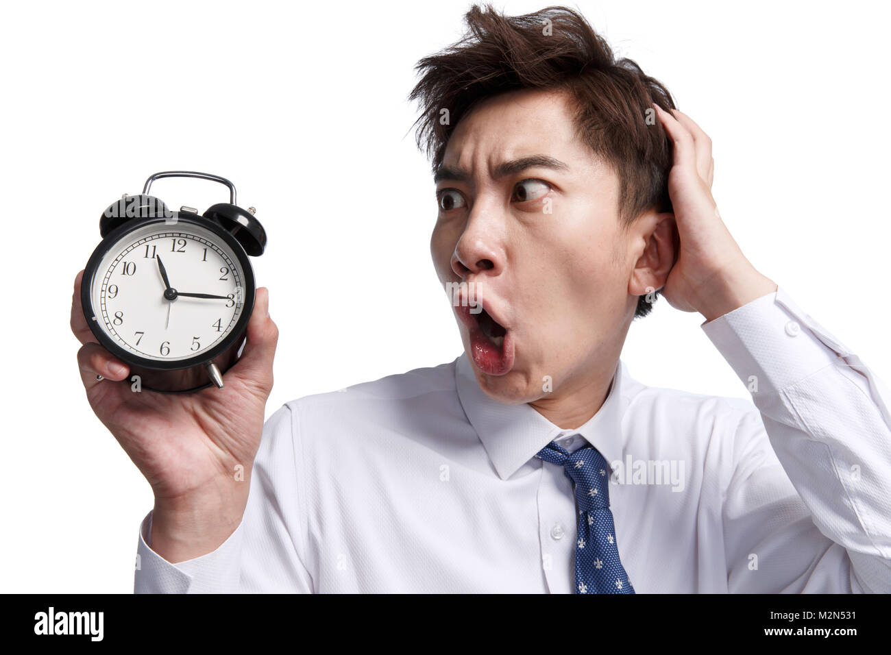 Shocking business young man with an alarm clock Stock Photo - Alamy