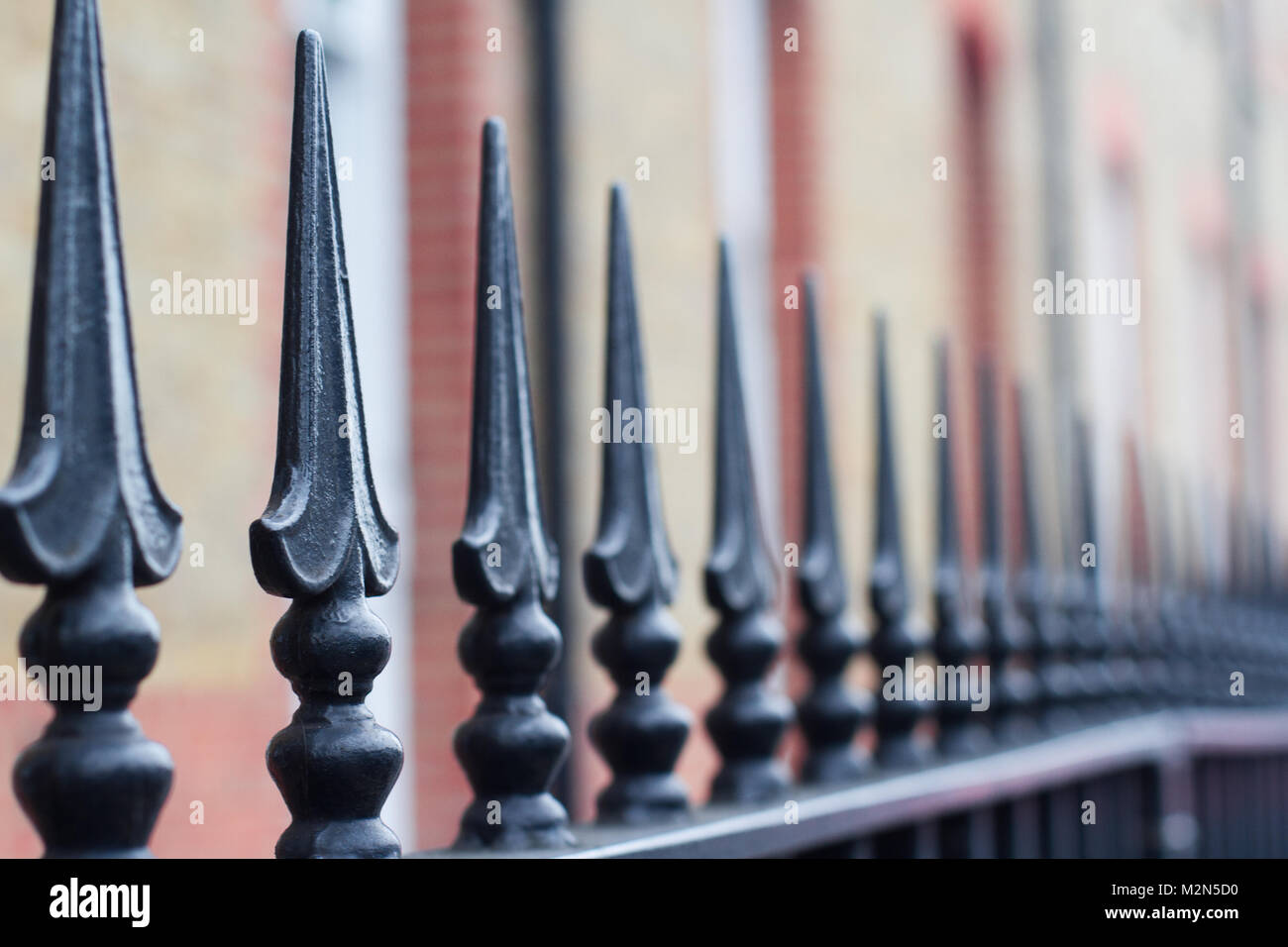 perspective horizontal view of black painted iron fence spikes in front ...