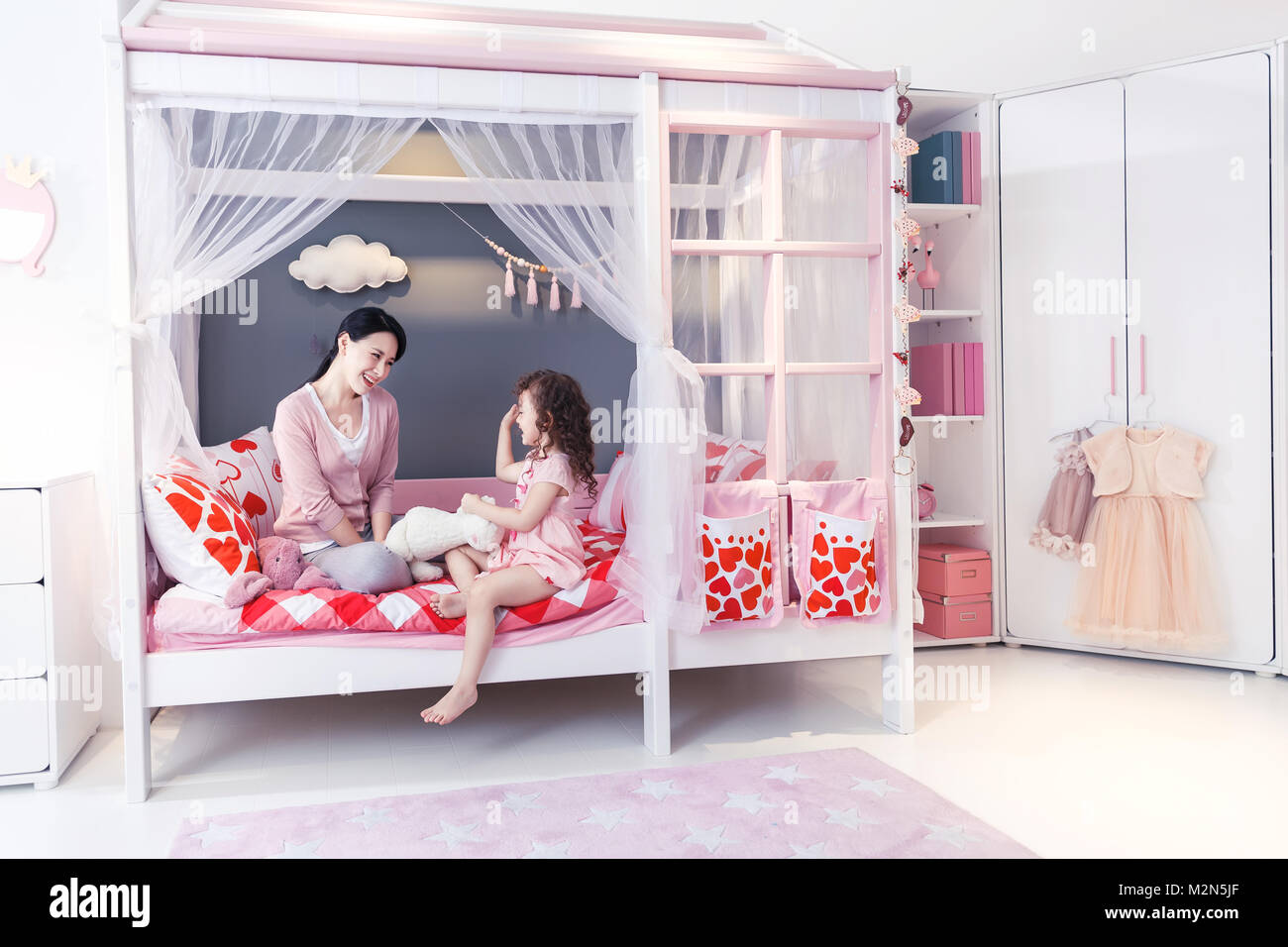 Cute little girl and her mother play in the bedroom Stock Photo - Alamy