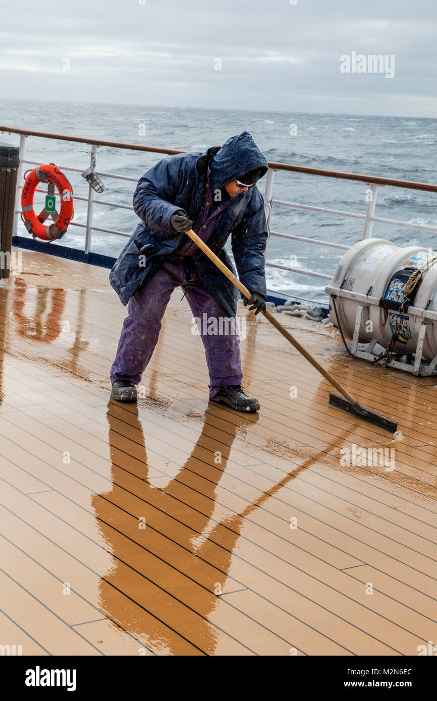 Deckhand in foul weather on deck of passenger ship Ocean Adventurer ...