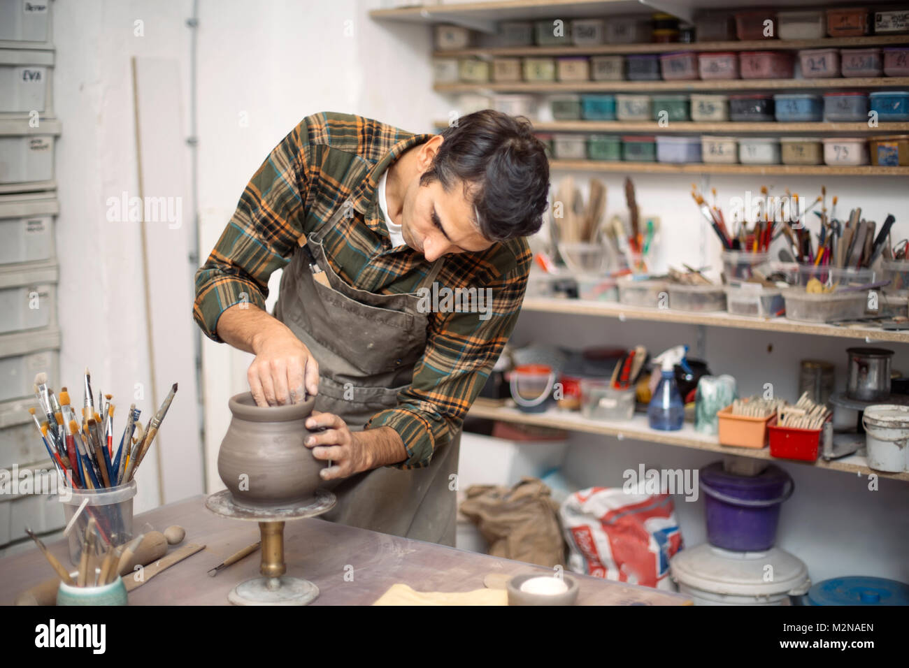 Young man making and decorating pottery in workshop Stock Photo - Alamy