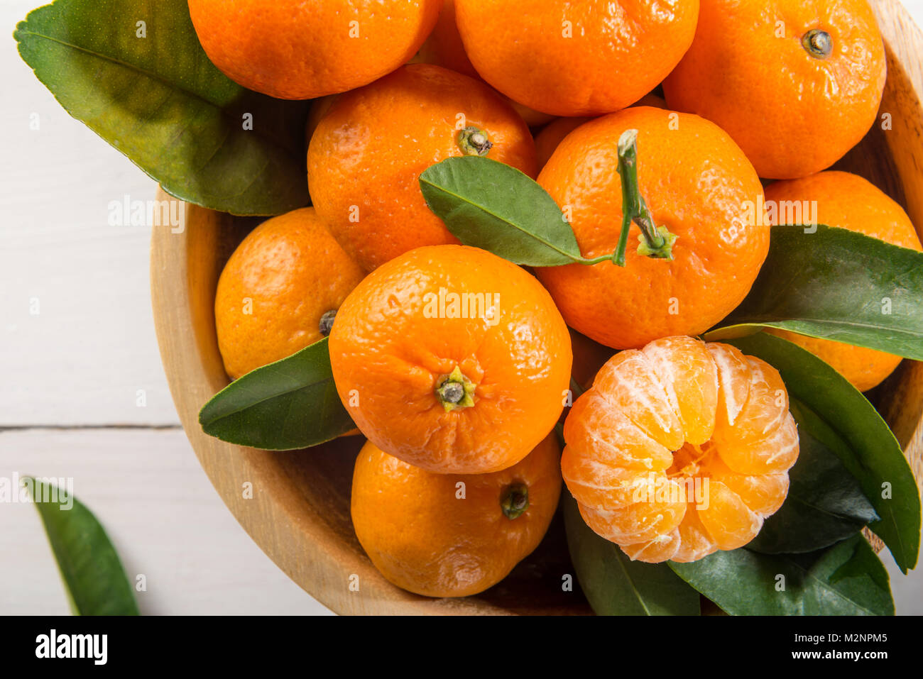 Delicious and beautiful mini Tangerines with leaves in the wooden bowl ...