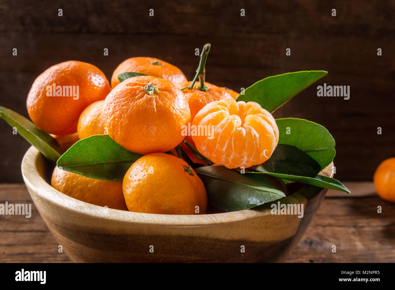 Delicious and beautiful mini Tangerines with leaves in the wooden bowl ...