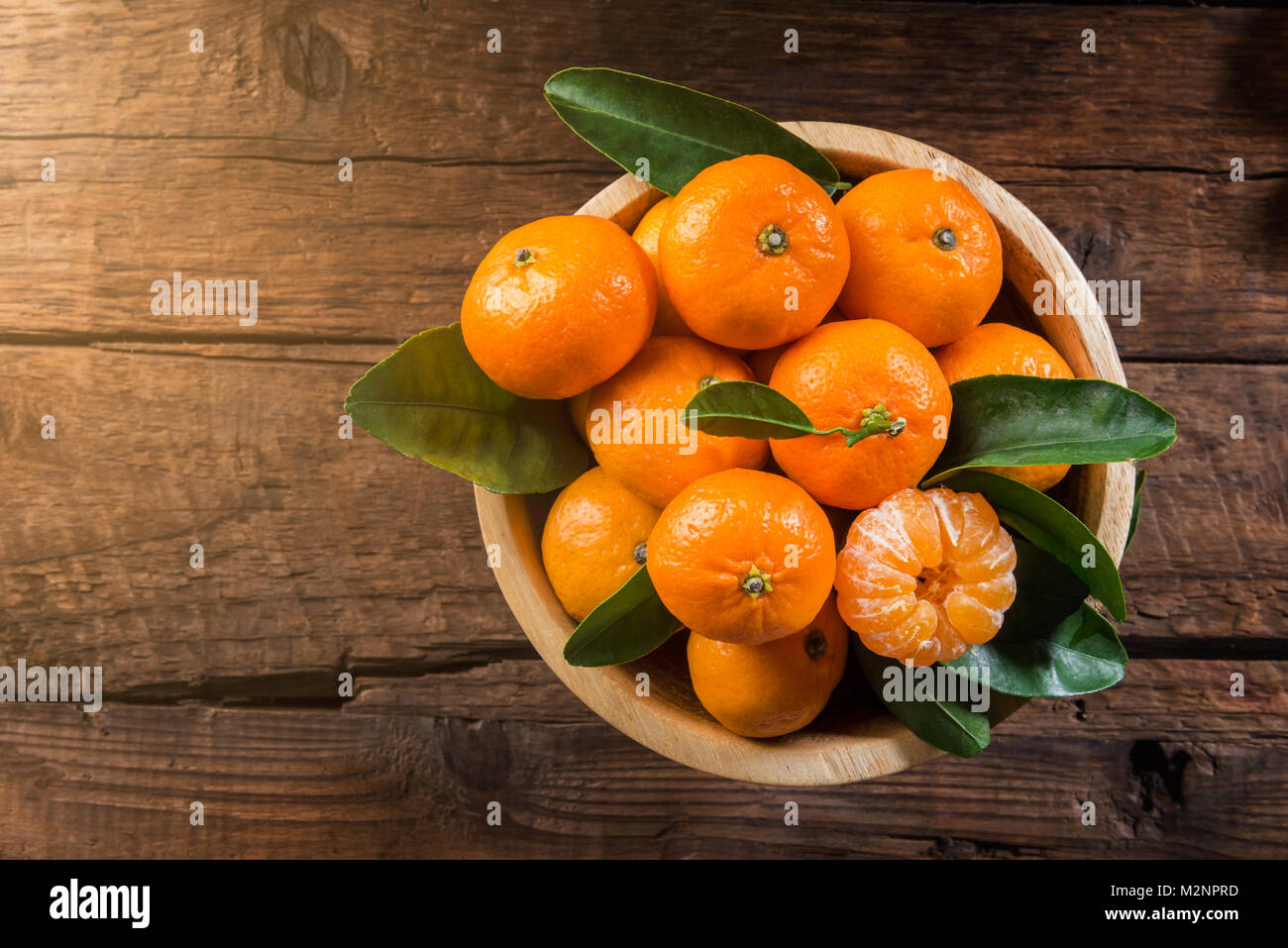 Delicious and beautiful mini Tangerines with leaves in the wooden bowl ...
