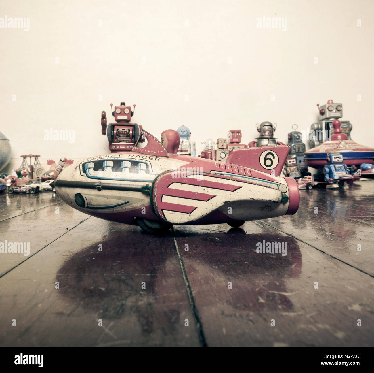 small red retro rocket toy on a wooden floor with retro robots in the ...