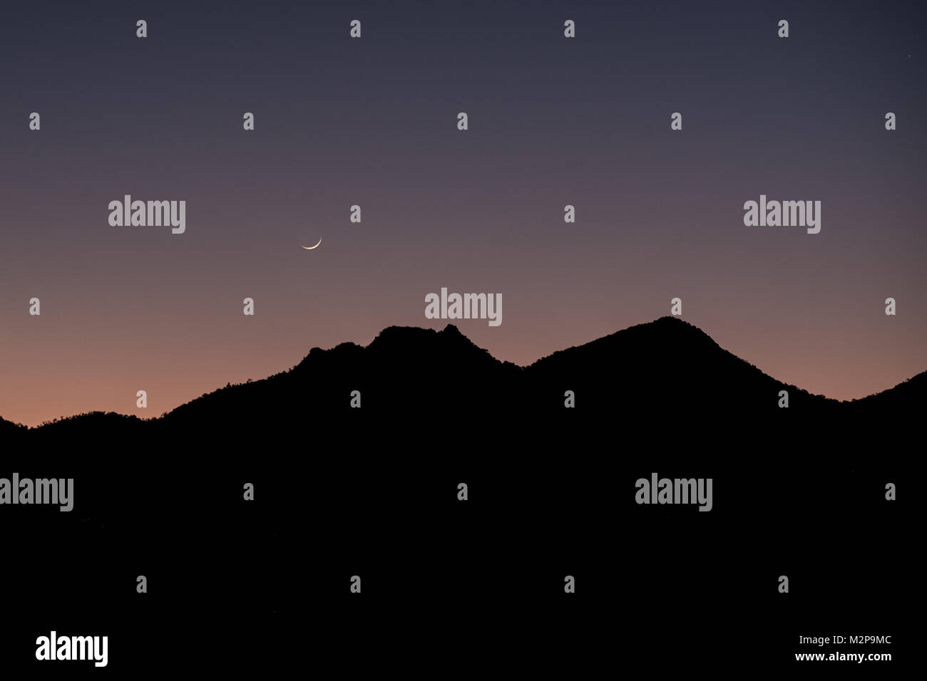 Moon appears during sunset over mountains in Rio de Janeiro, Brazil ...