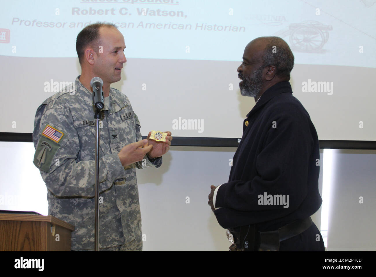 Col. Andy Backus, presents his commander’s coin to Robert C. Watson, an ...
