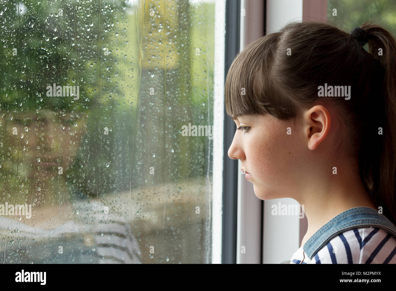Sad child looking through window Stock Photo - Alamy