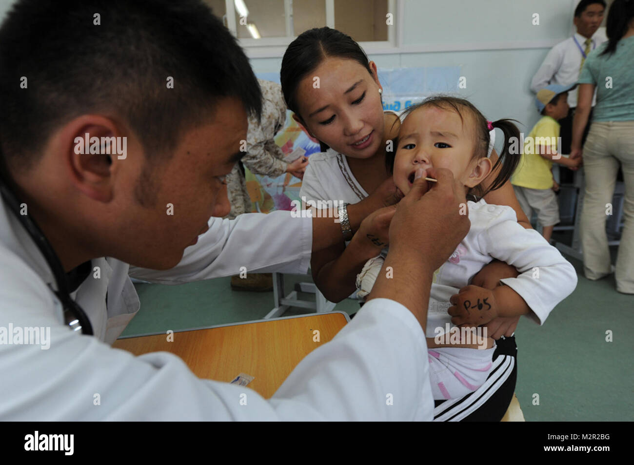 ULAANBAATAR, Mongolia – Mongolian doctor, Bilgee Butbily attempts to look in a young girl's ...