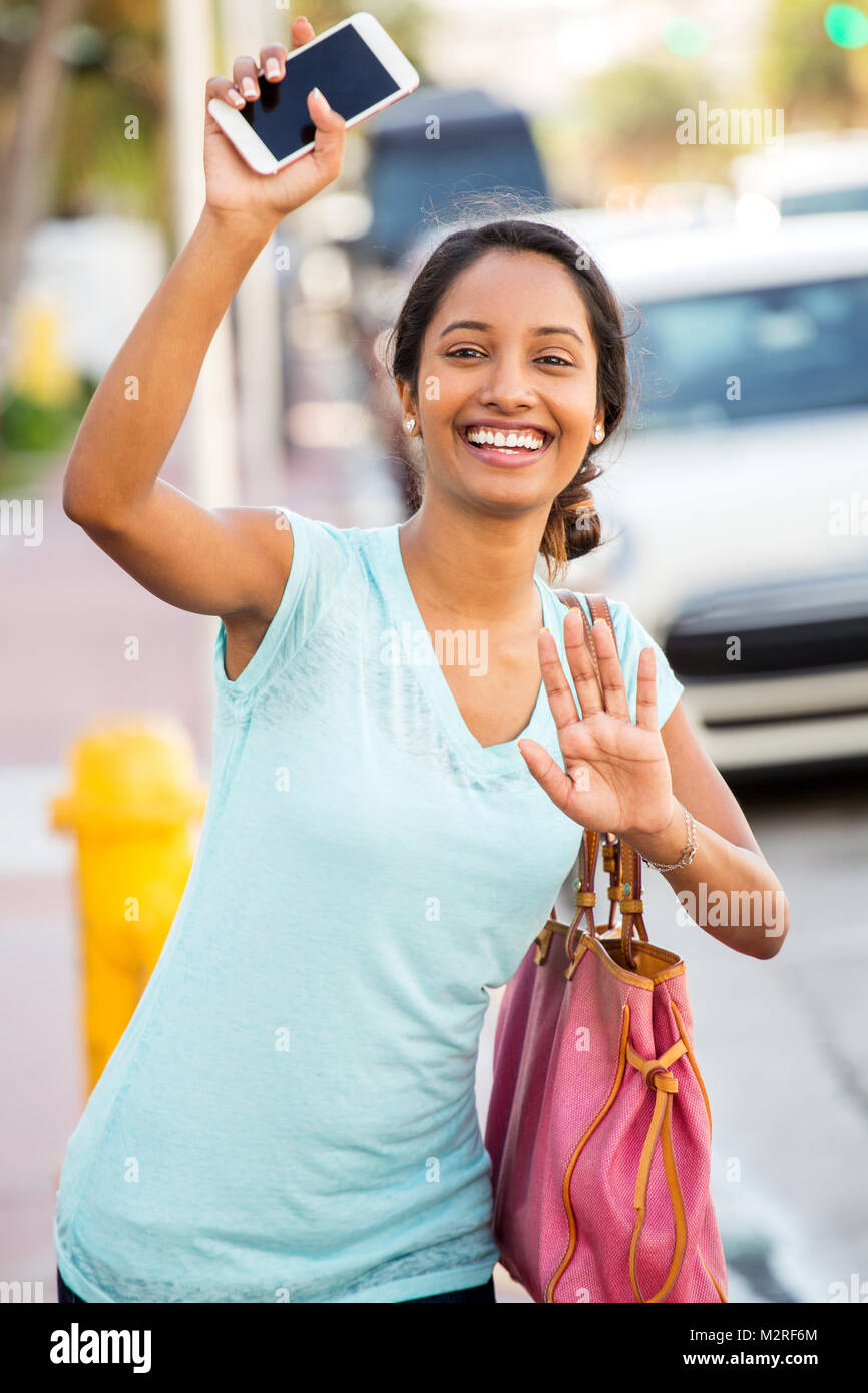 Young woman waving her hand for her ride Stock Photo - Alamy