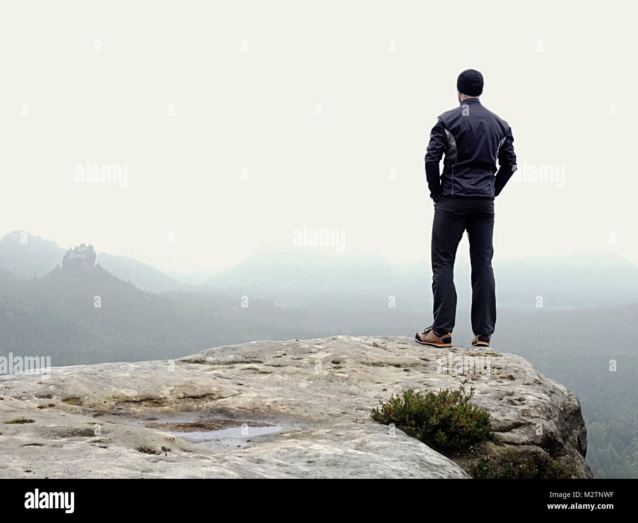 Nature hiker on sharp cliff roc watching over misty valley to blurred ...
