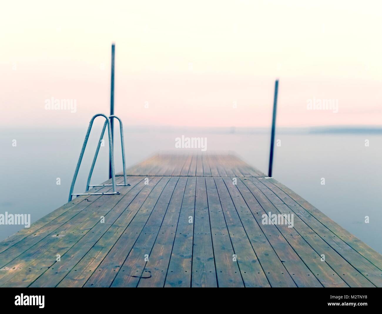 Wet wooden pier in smooth water of sea bay. Old mole anchored with ...