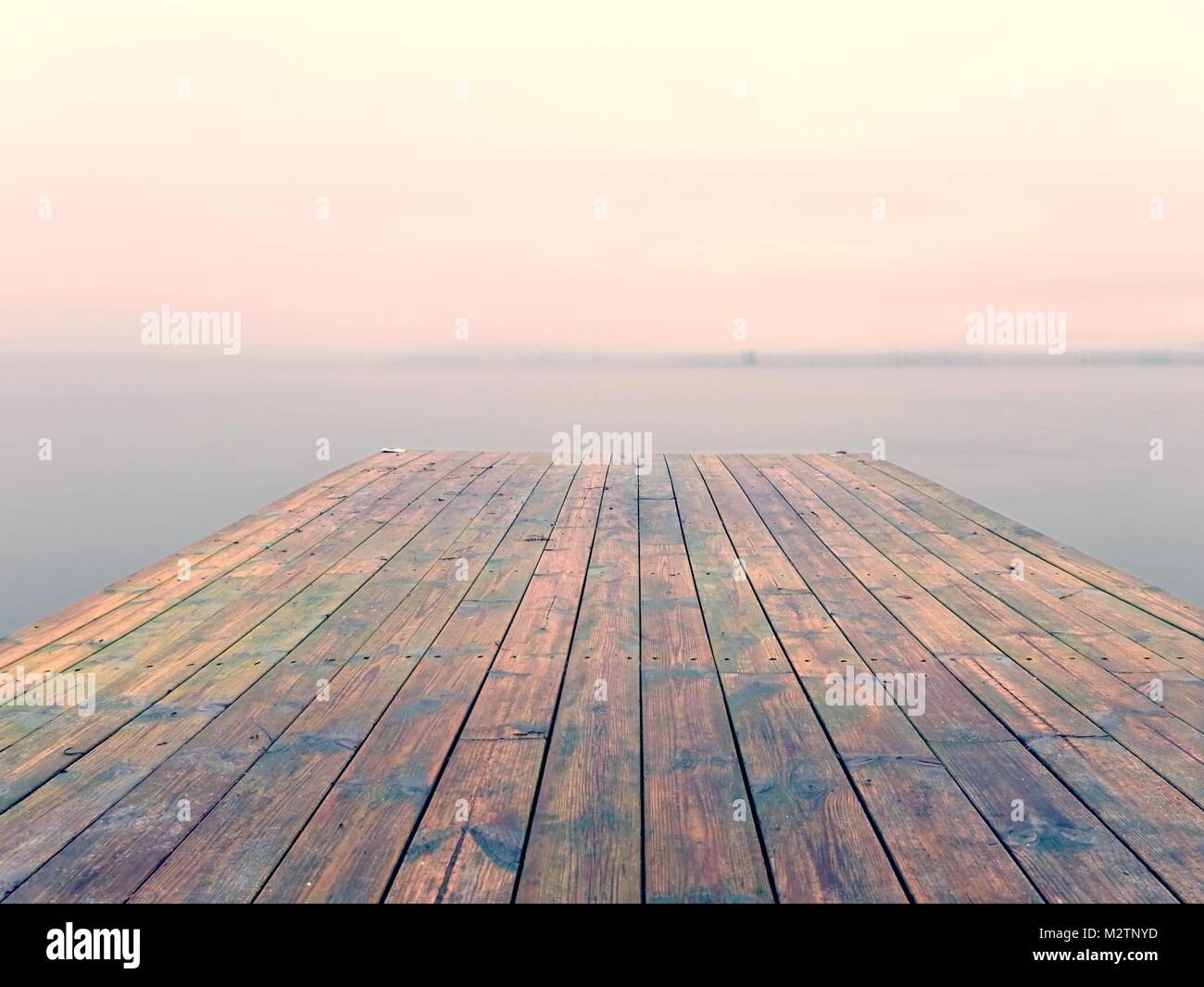 Wet wooden pier in smooth water of sea bay. Old mole anchored with ...