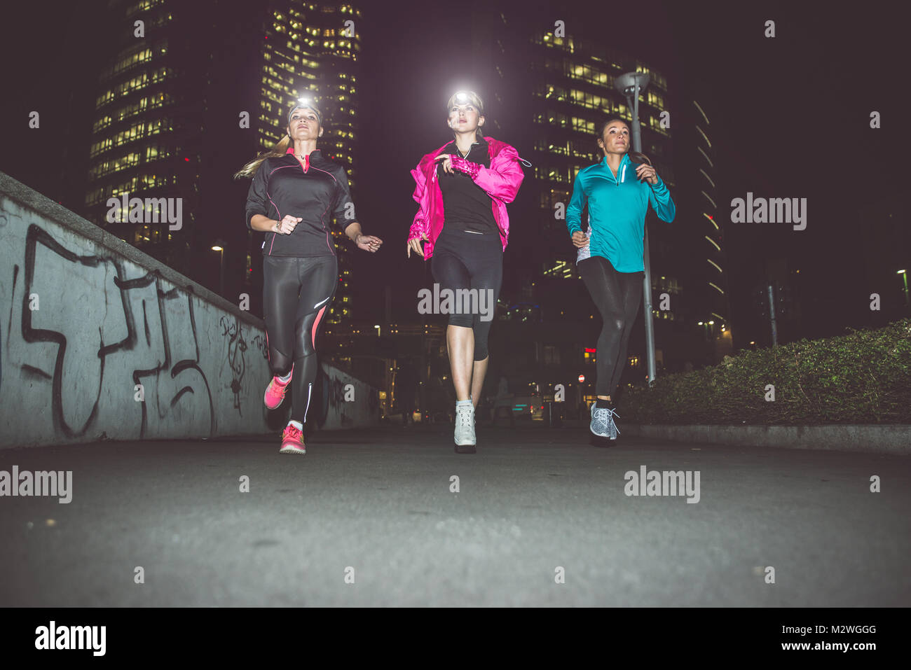 Three women running in the night in the city center Stock Photo - Alamy