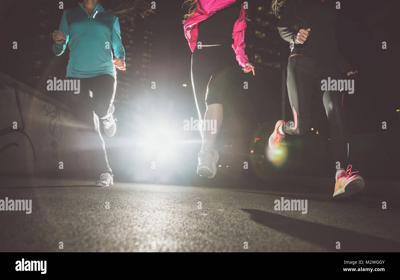Three women running in the night in the city center Stock Photo - Alamy