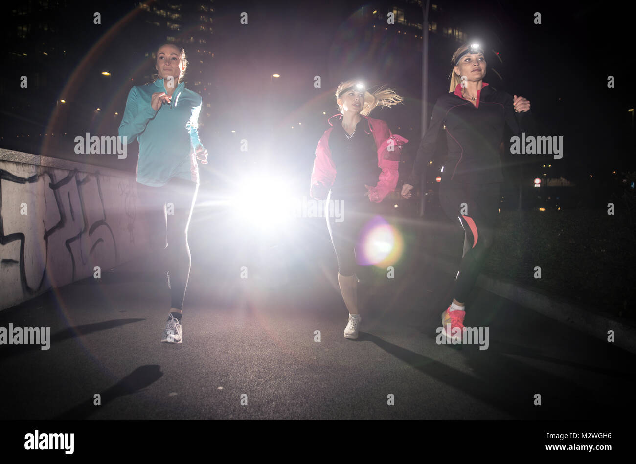 Three women running in the night in the city center Stock Photo - Alamy