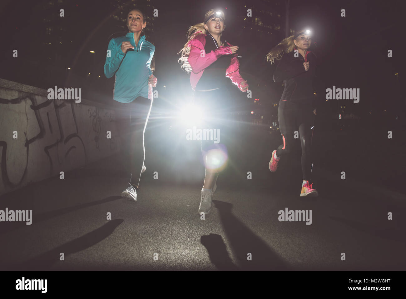 Three women running in the night in the city center Stock Photo - Alamy