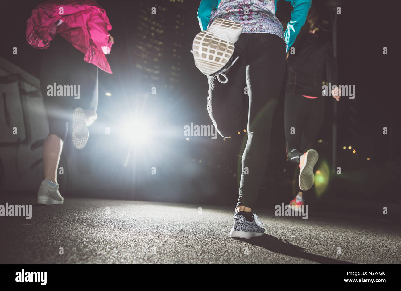 Three women running in the night in the city center Stock Photo - Alamy