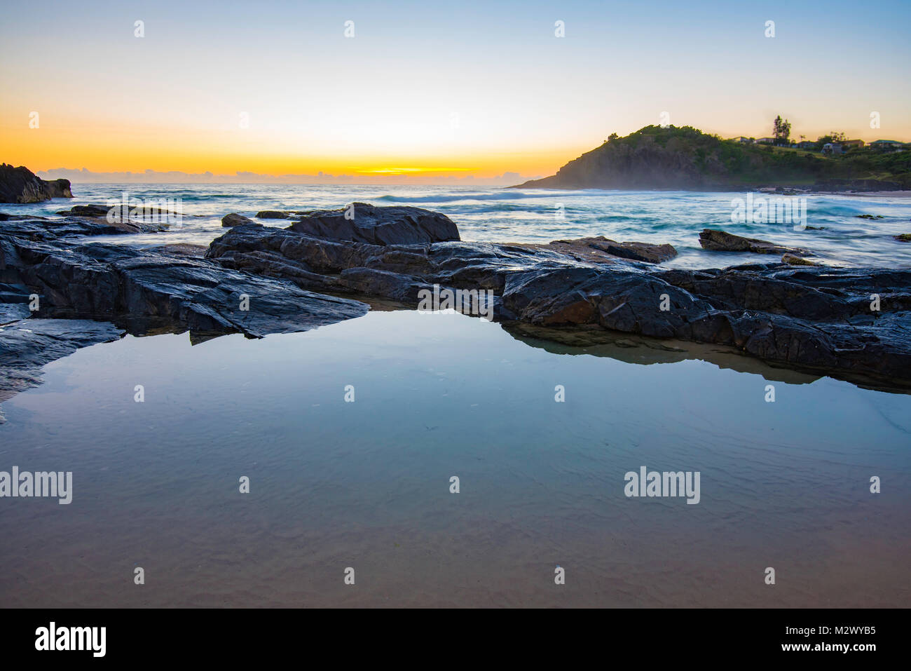 Sunrise over a mirror surface on a small rock pool near Little Beach at ...