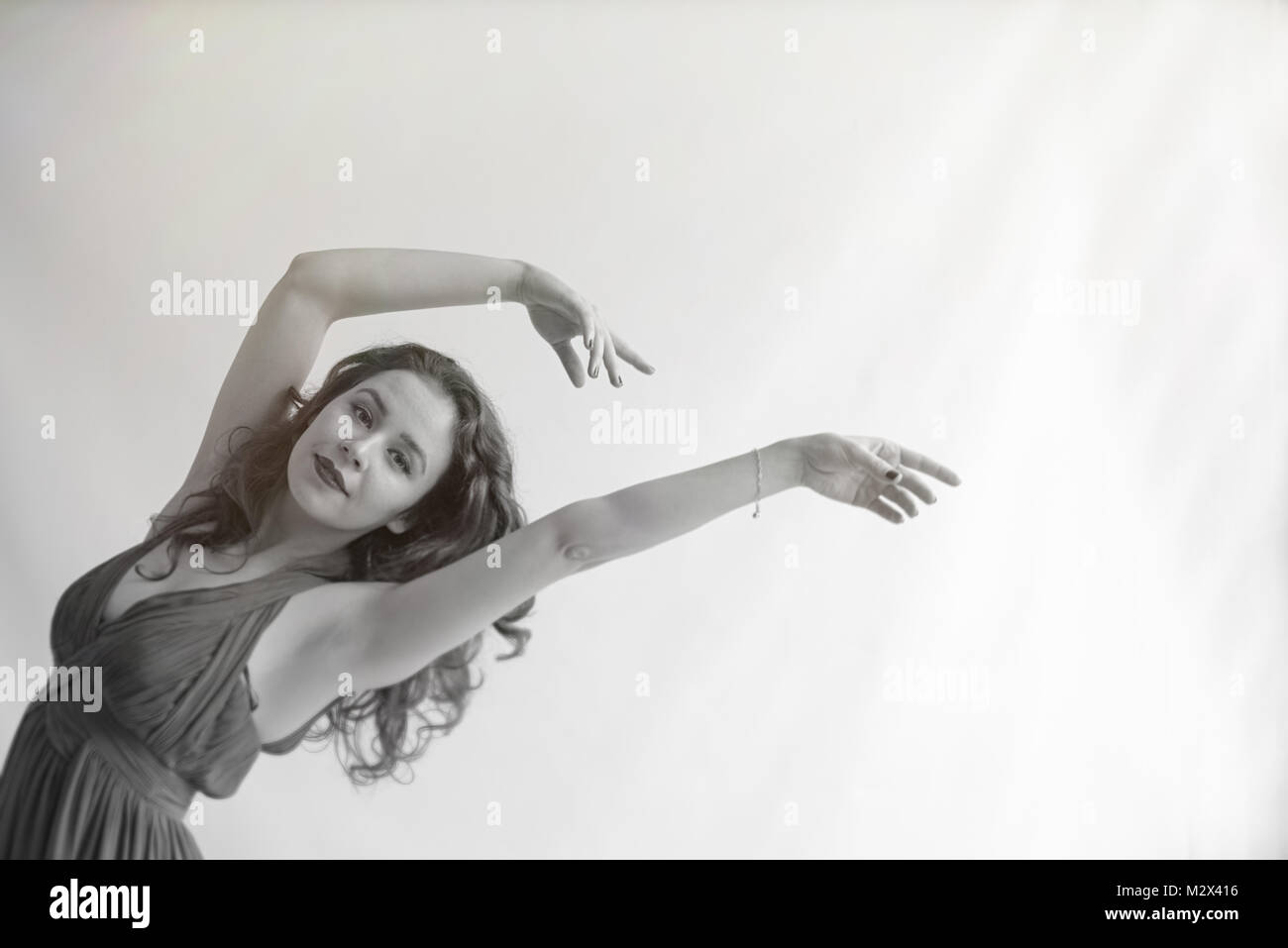 Beautiful classically dressed young girl dances across a grey backdrop ...