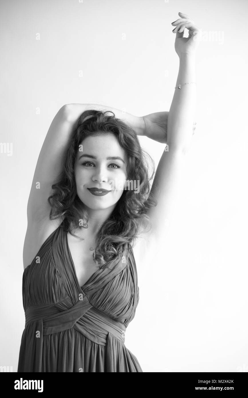 Beautiful classically dressed young girl dances across a grey backdrop ...