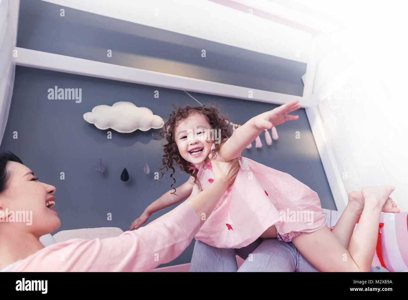 Cute little girl and her mother play in the bedroom Stock Photo - Alamy