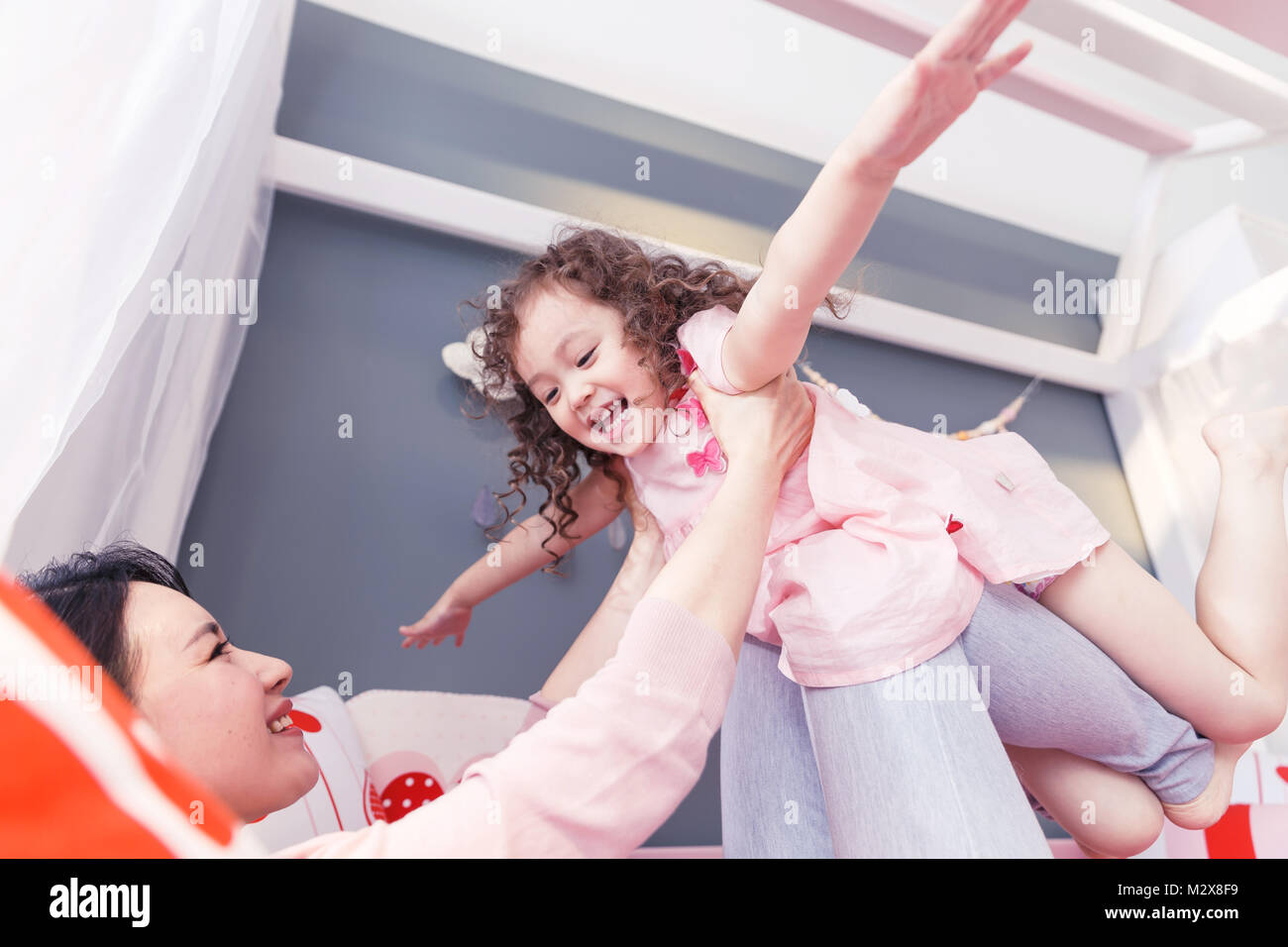 Cute little girl and her mother play in the bedroom Stock Photo - Alamy