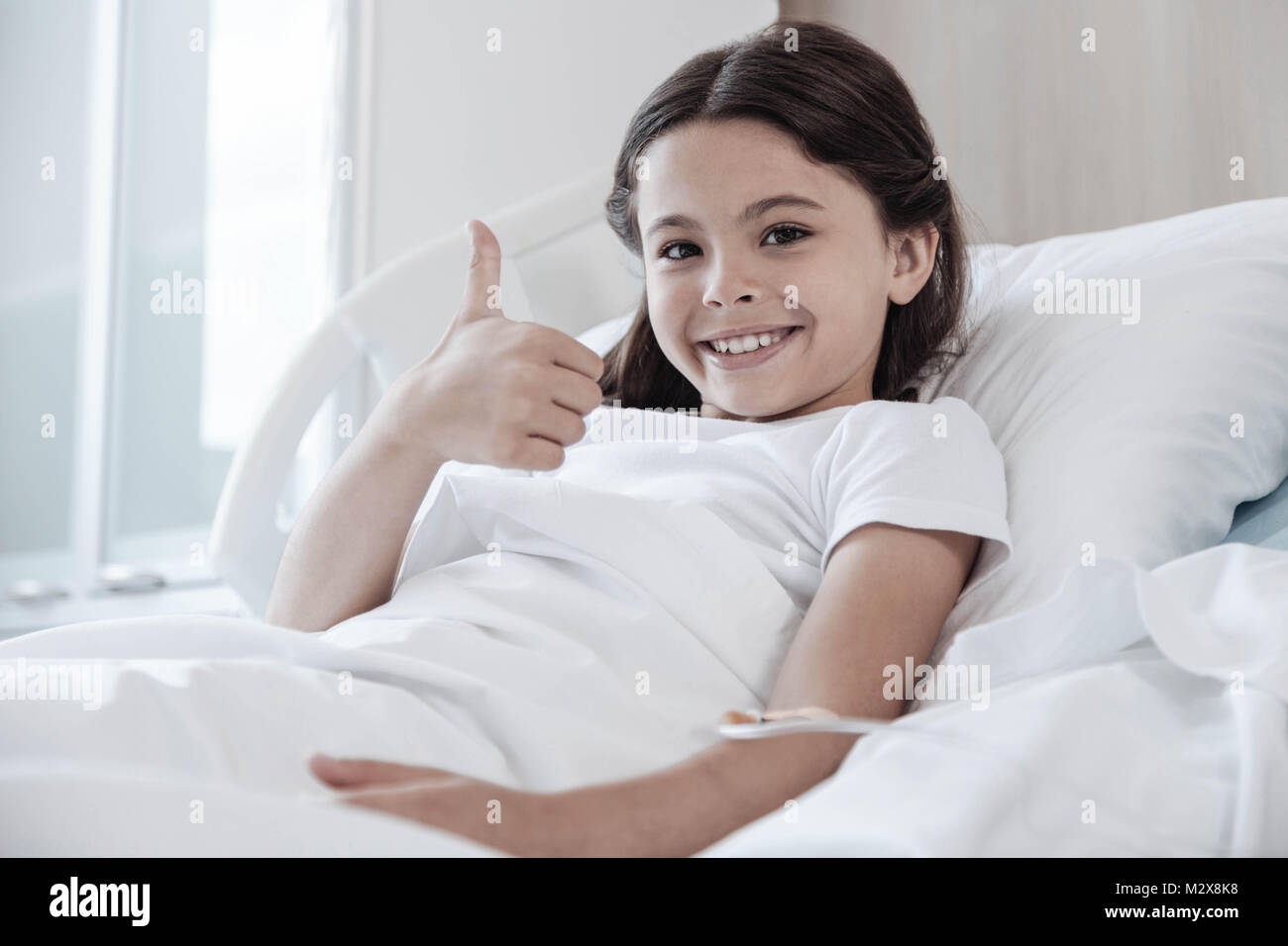 Brave little patient smiling and thumbing up in hospital bed Stock ...