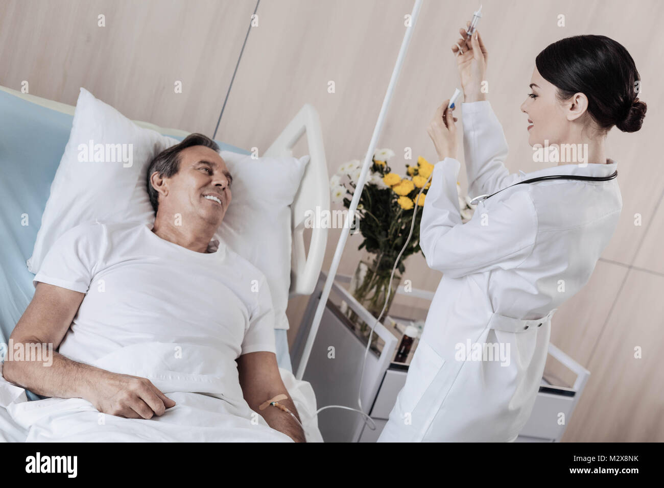 Smiling doctor adjusting drop counter for ill male patient Stock Photo ...