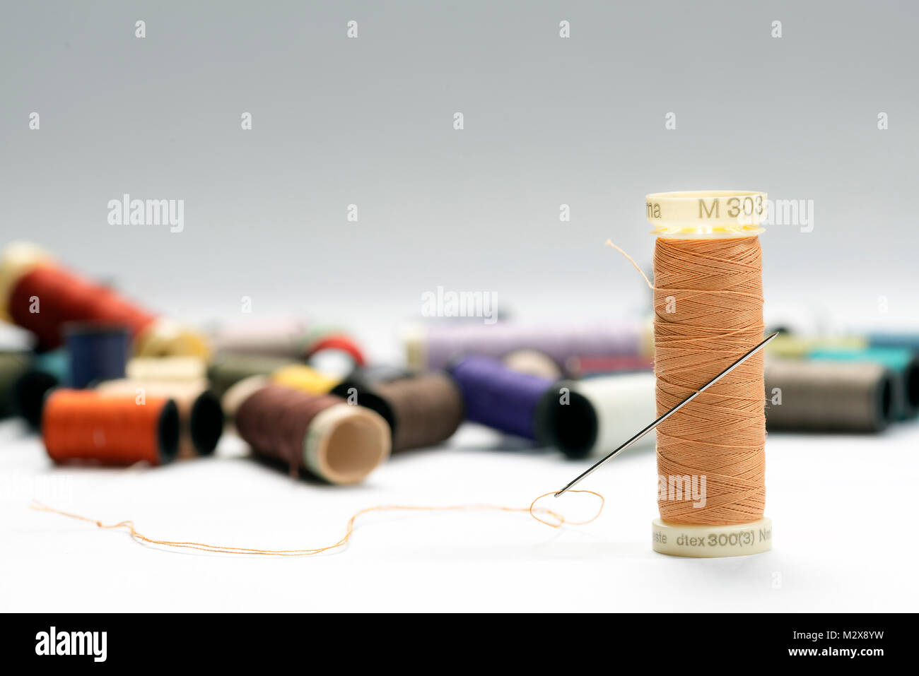 sewing threads and needle on a white background Stock Photo - Alamy