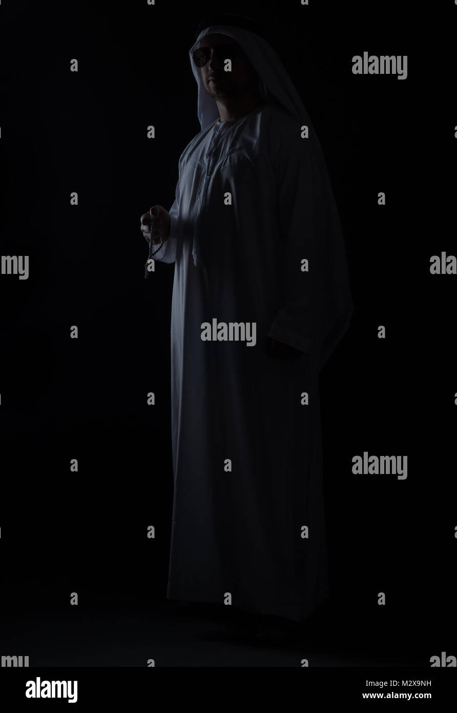 low key shot of standing sheik with sunglasses in front of black ...