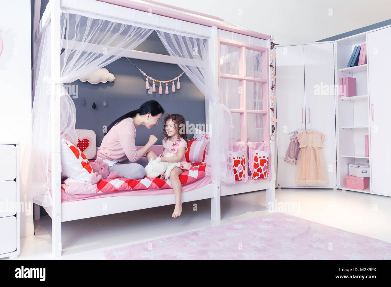 Cute little girl and her mother play in the bedroom Stock Photo - Alamy