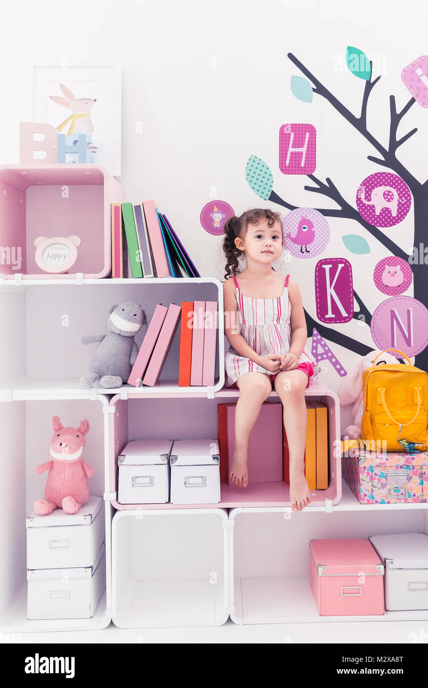 Lovely little girl sitting on a shelf Stock Photo - Alamy