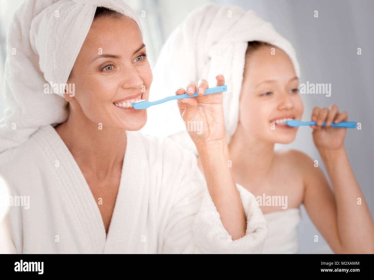 Delighted nice woman brushing teeth together with daughter Stock Photo ...