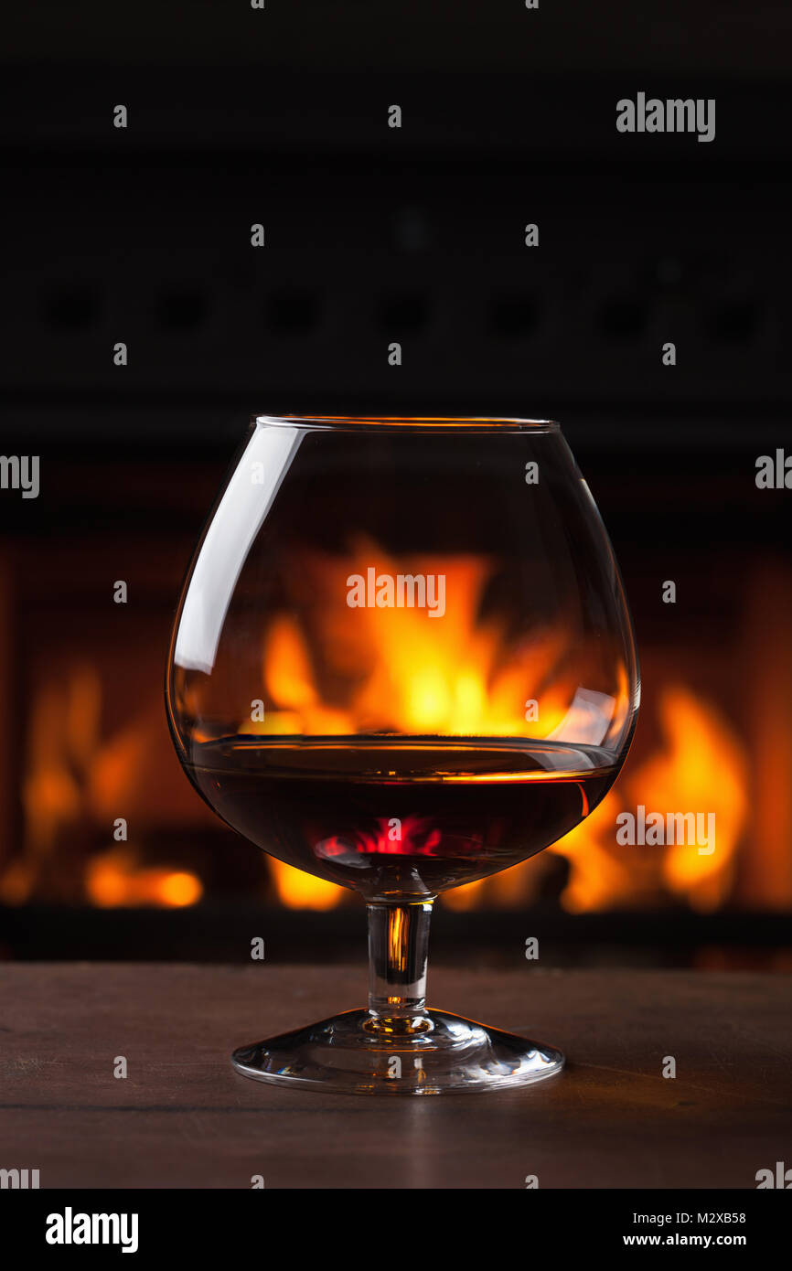a glass of cognac in front of fireplace Stock Photo - Alamy