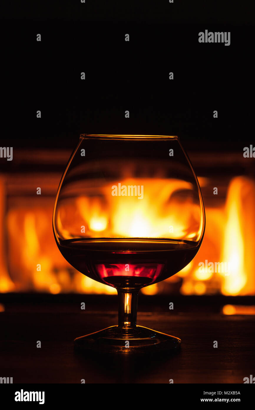 a glass of cognac in front of fireplace Stock Photo - Alamy