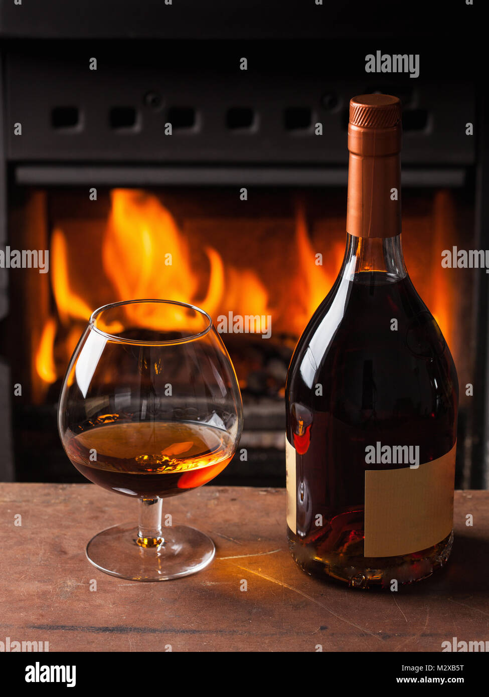 a glass of cognac in front of fireplace Stock Photo - Alamy